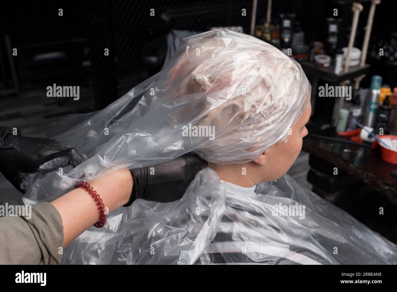 The hands of a professional hairdresser fix a plastic film on the ...
