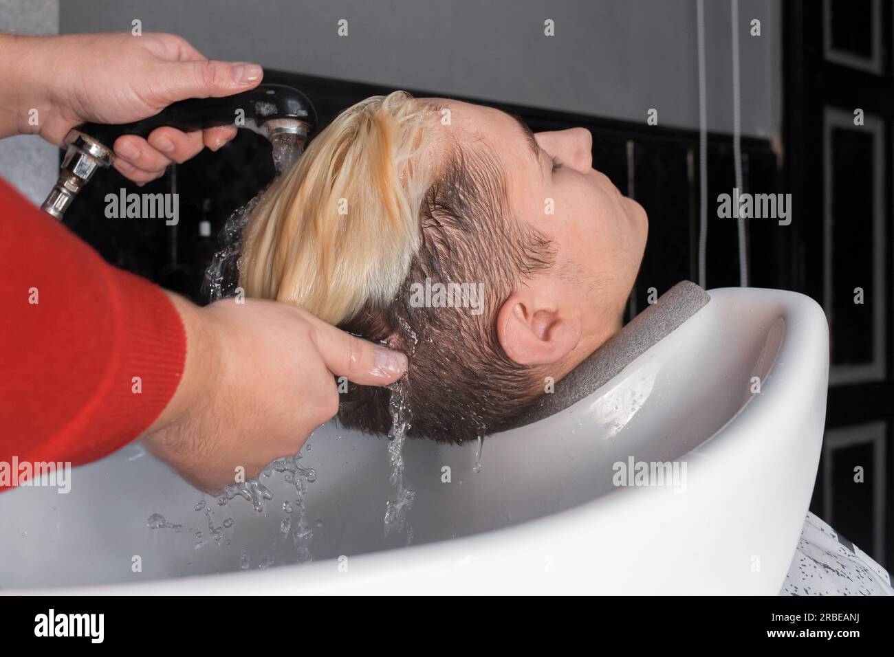 The hairdresser's hands wash the client's hair with rain and water over ...