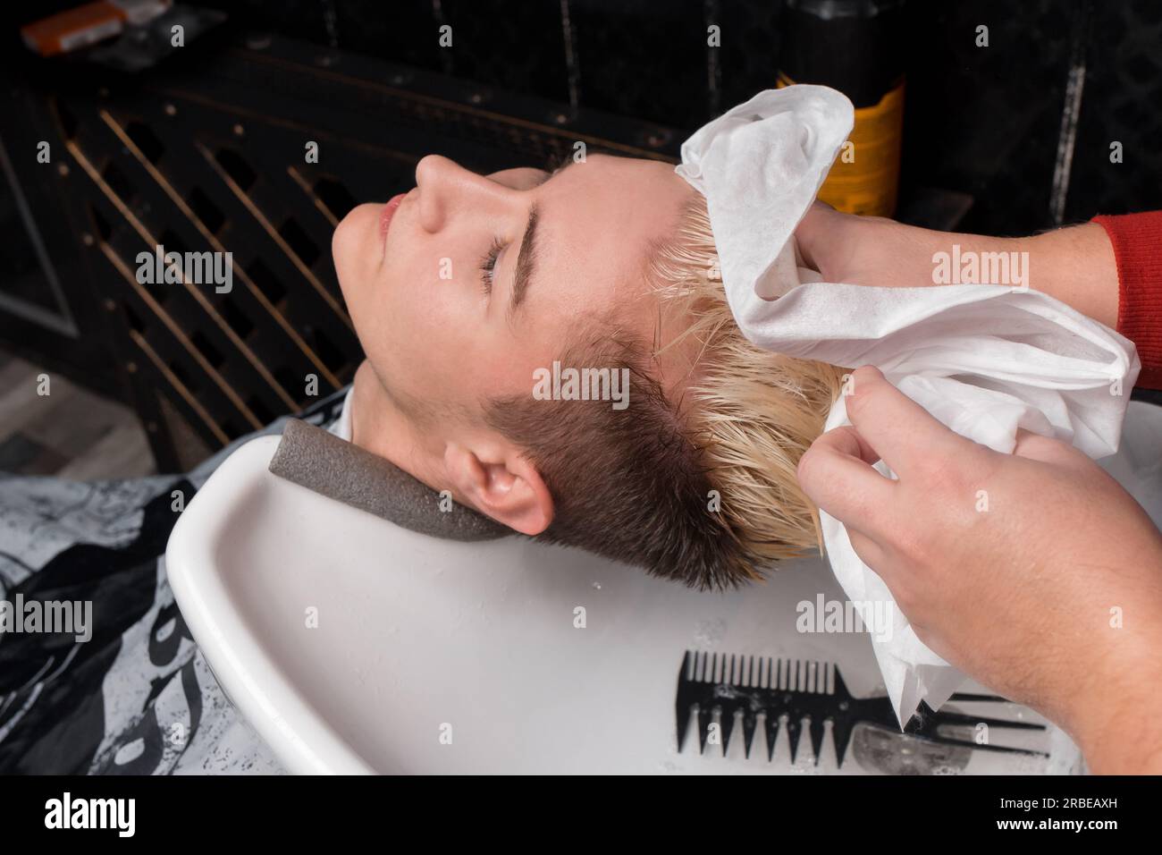 The hands of a barbershop employee wipe the hair on the head, of a guy ...
