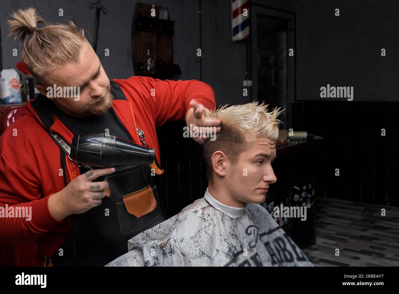 Stylish professional European man barber blow-drying hair for a client ...