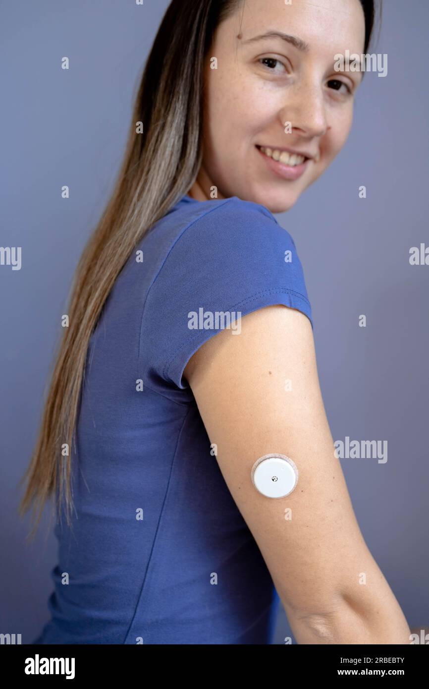 Girl sitting with sensor glucose patch on her arm Stock Photo - Alamy