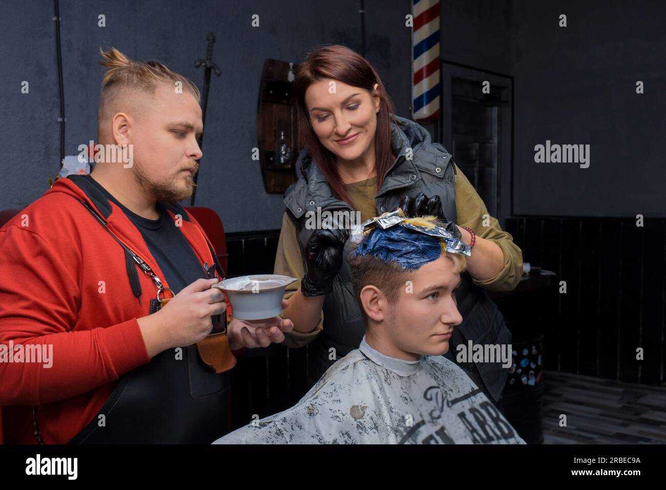A smiling pretty woman, a professional barber and a man dye their hair ...