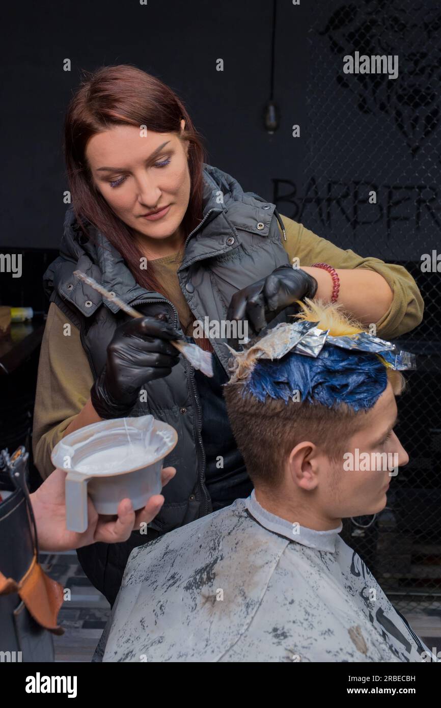 Professional girl hairdresser beautiful European at work in the process ...