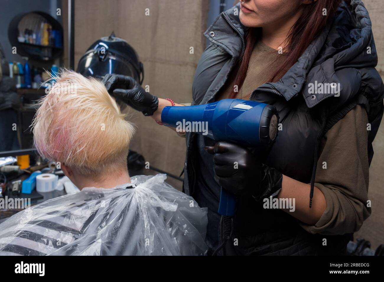 Hand in the glove of an experienced salon worker girl blow drying hair ...