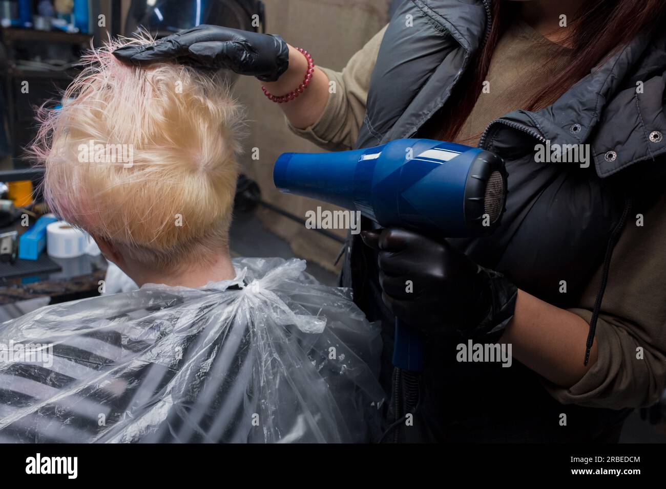 The hands of a professional barber girl work with a client, dry the ...