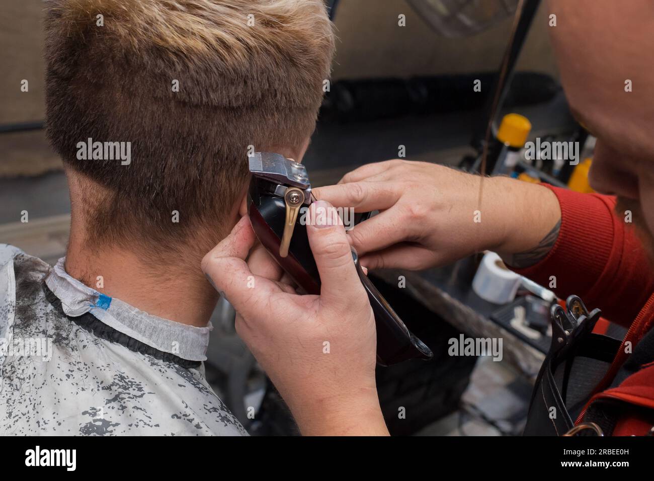 The hands of a man of a professional salon worker shave the area in the ...