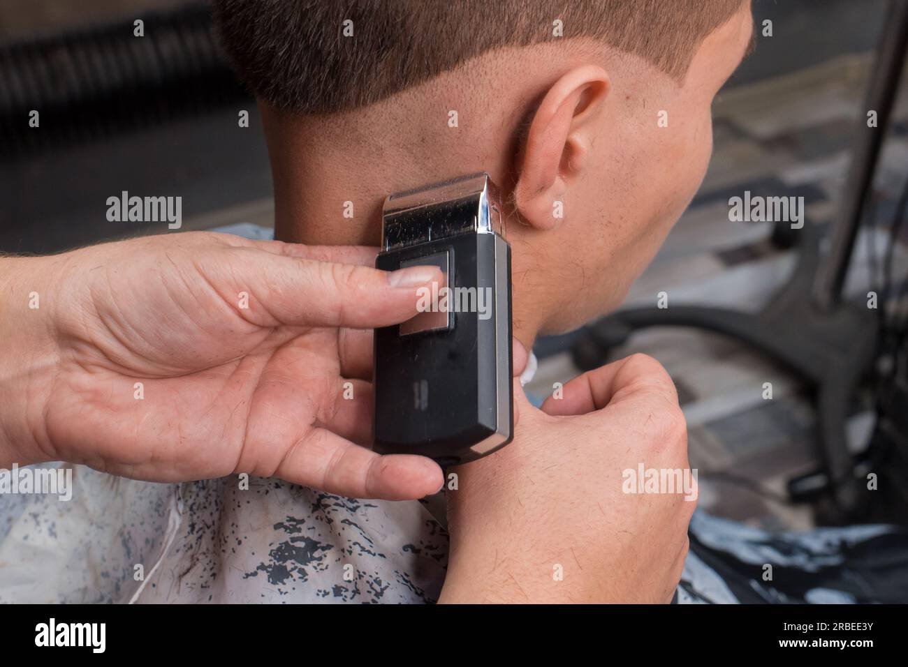 The hairdresser's hands cut the back of the head and a fashionable ...