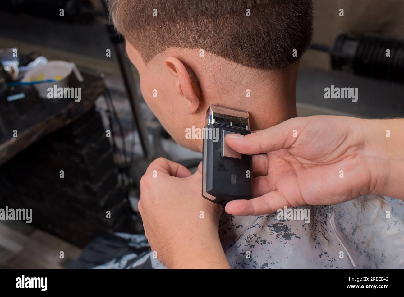 The barber's hands cut the back of the head of the client's young guy ...