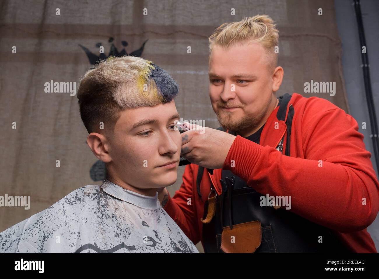 A positive adult guy, a barbershop worker, a Caucasian, cuts the hair ...