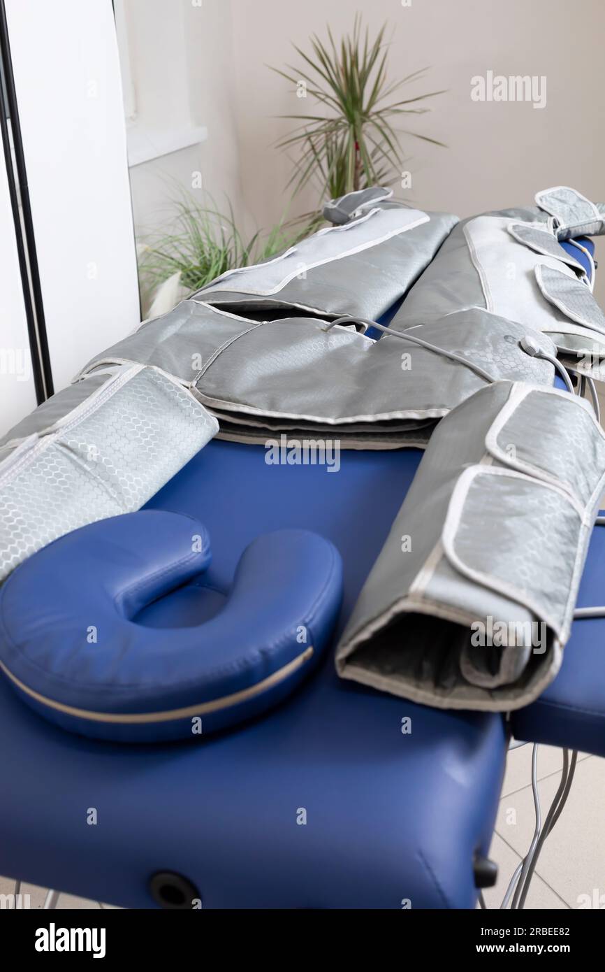 Pressure therapy gray massaging suit on blue couch in spa, treatment of ...