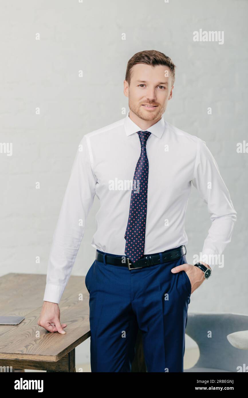 Attractive man in formal attire poses in office, works on new business ...