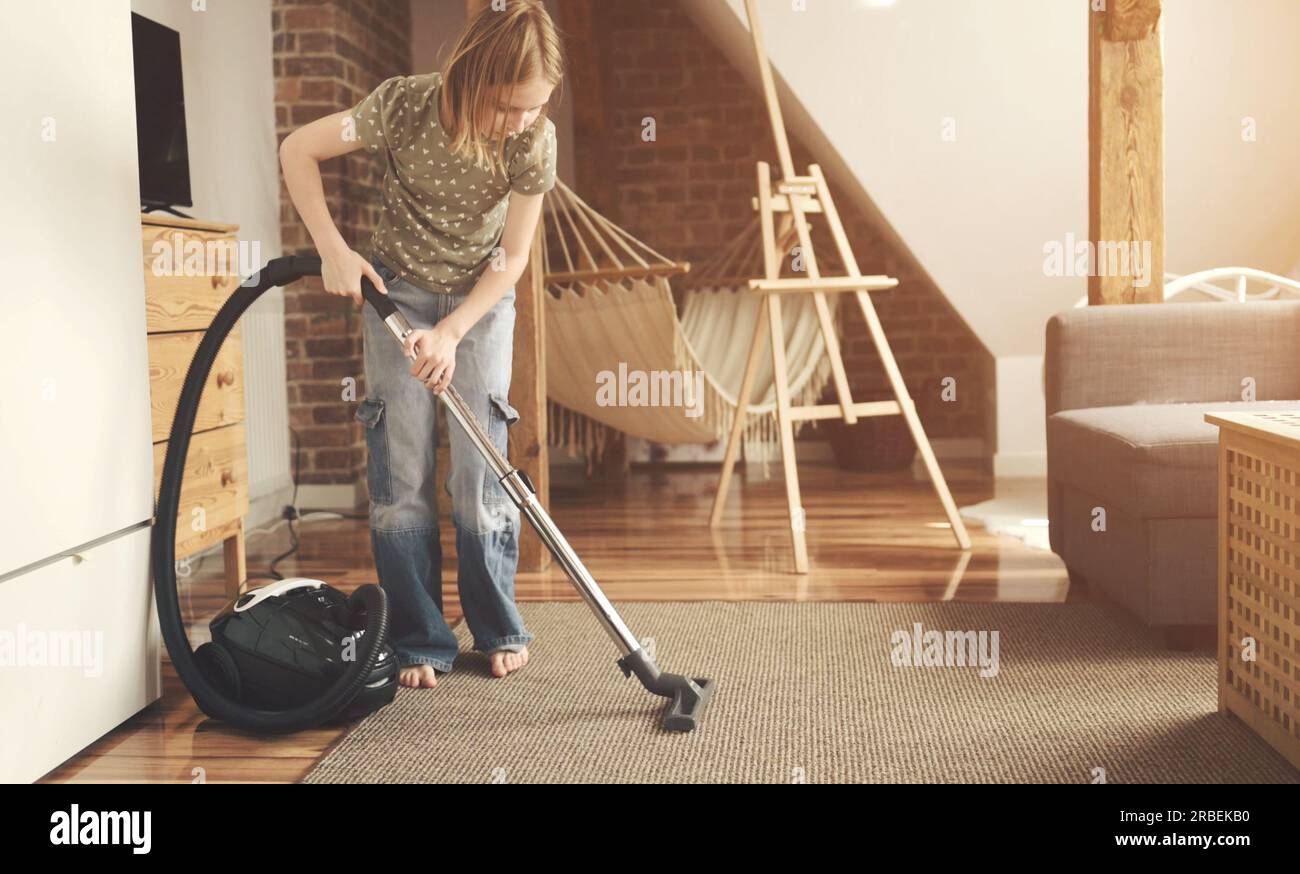 Girl child cleaning carpet with vacuum cleaner from dust at home ...