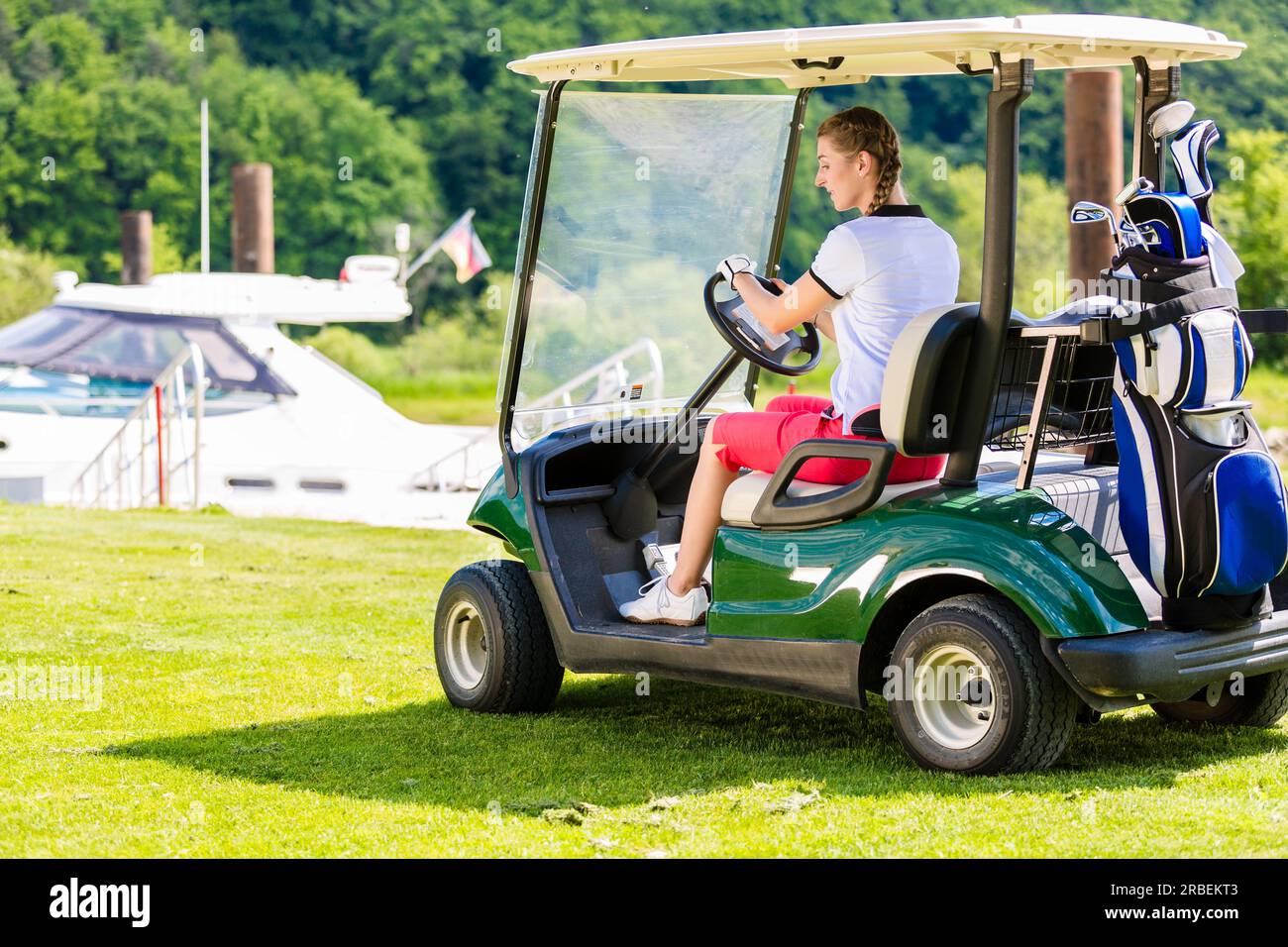 Female golf player riding on the golf cart at golf course on sunny day ...