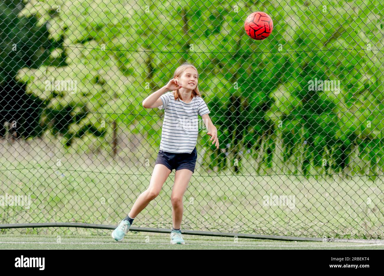 Pretty child girl catching football ball defending goal. Cute female ...