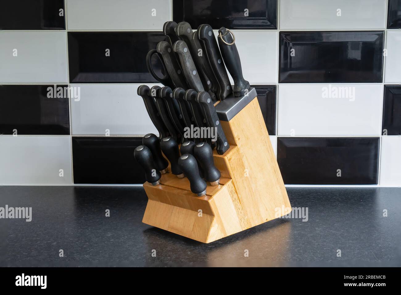 Wooden Knife Block on a dark kitchen top with black and white tiles ...