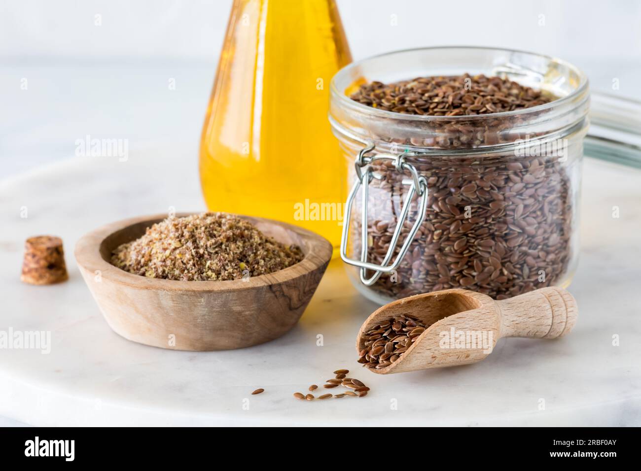 A close up of both ground and whole flax seeds with flax seed oil in ...