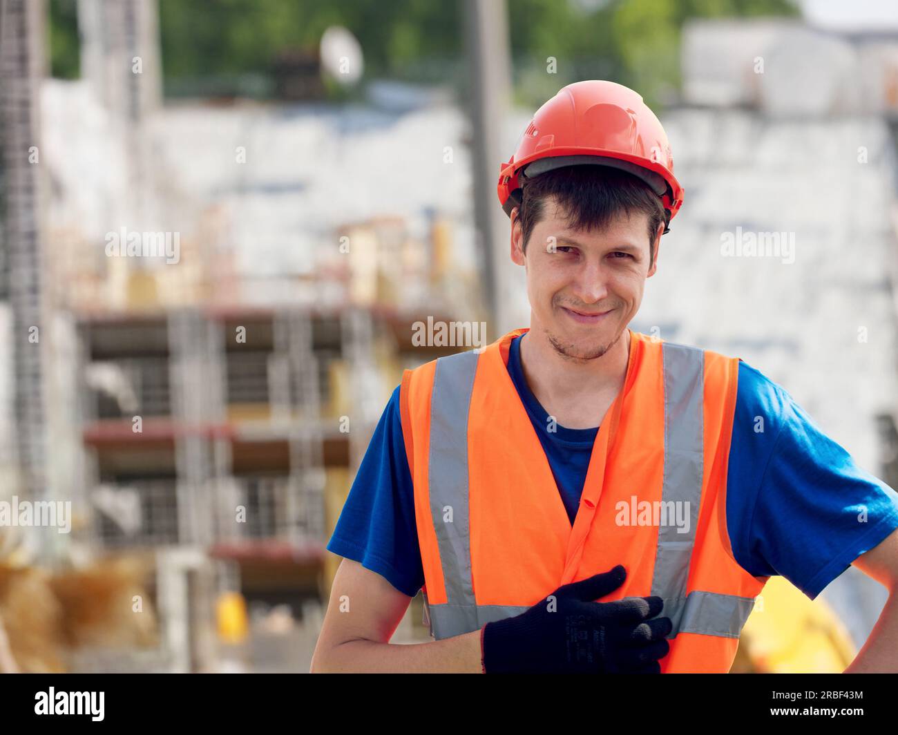 Portrait of young builder in construction helmet and flare vest on ...