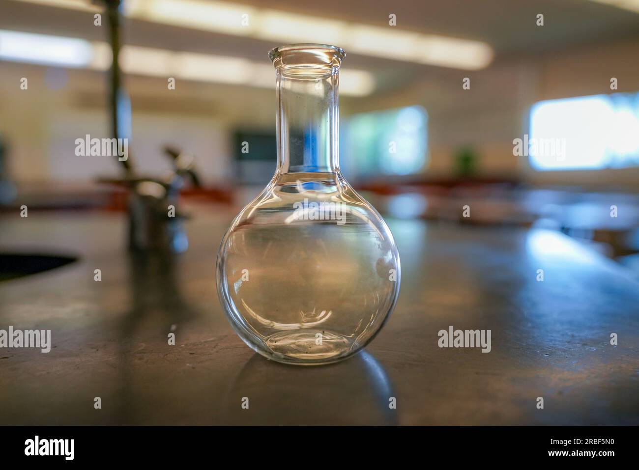 flask on a black resin table with a high school science room background ...
