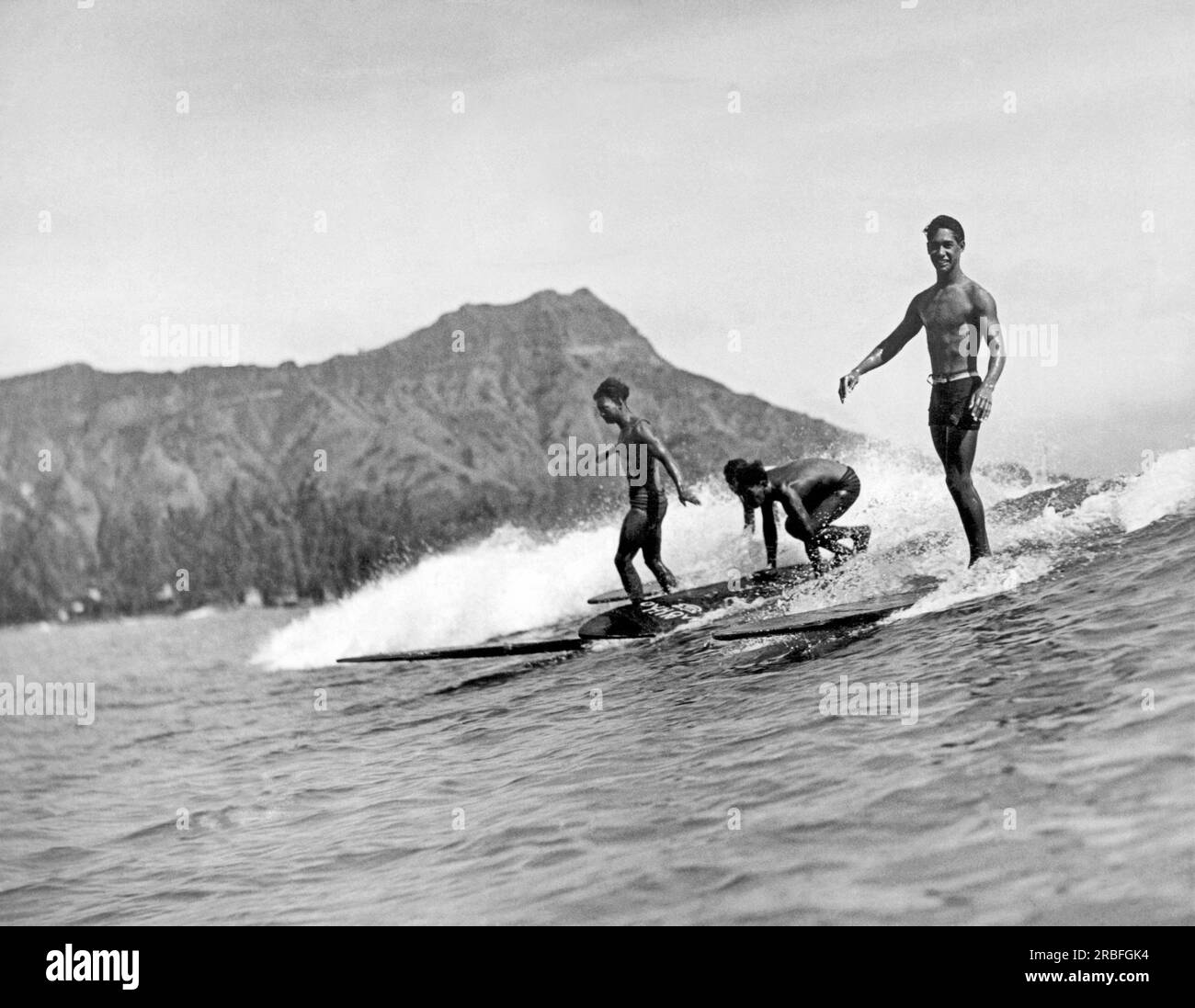 Honolulu, Hawaii: c. 1926. Three native surfers ride their boards with ...