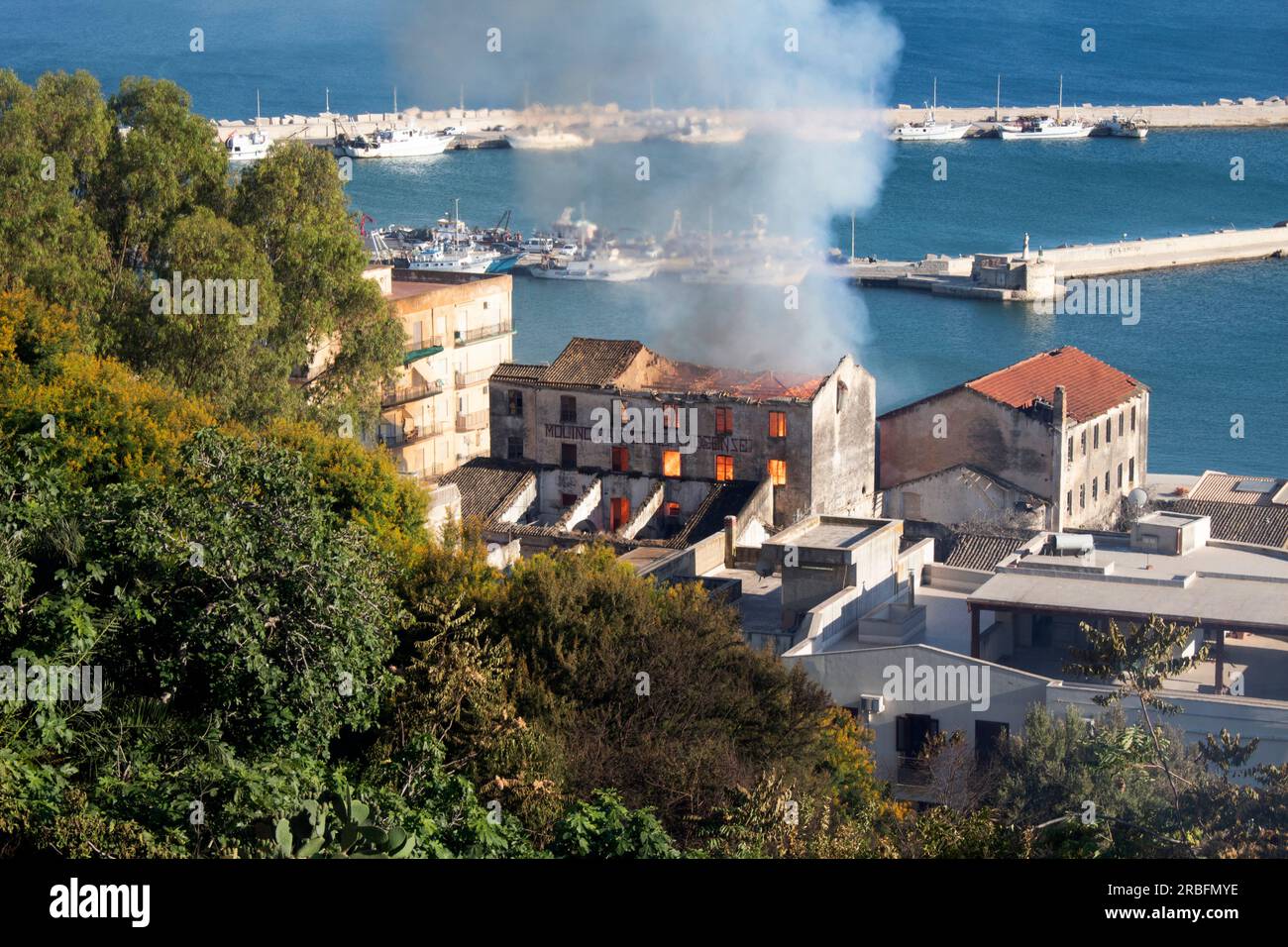 Flames appear at the window and smoke billows through the roof of a ...