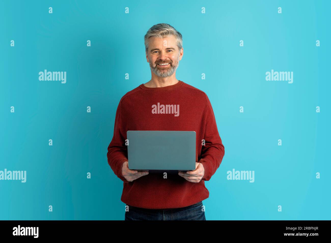 Positive middle aged man using modern pc laptop, blue background Stock ...
