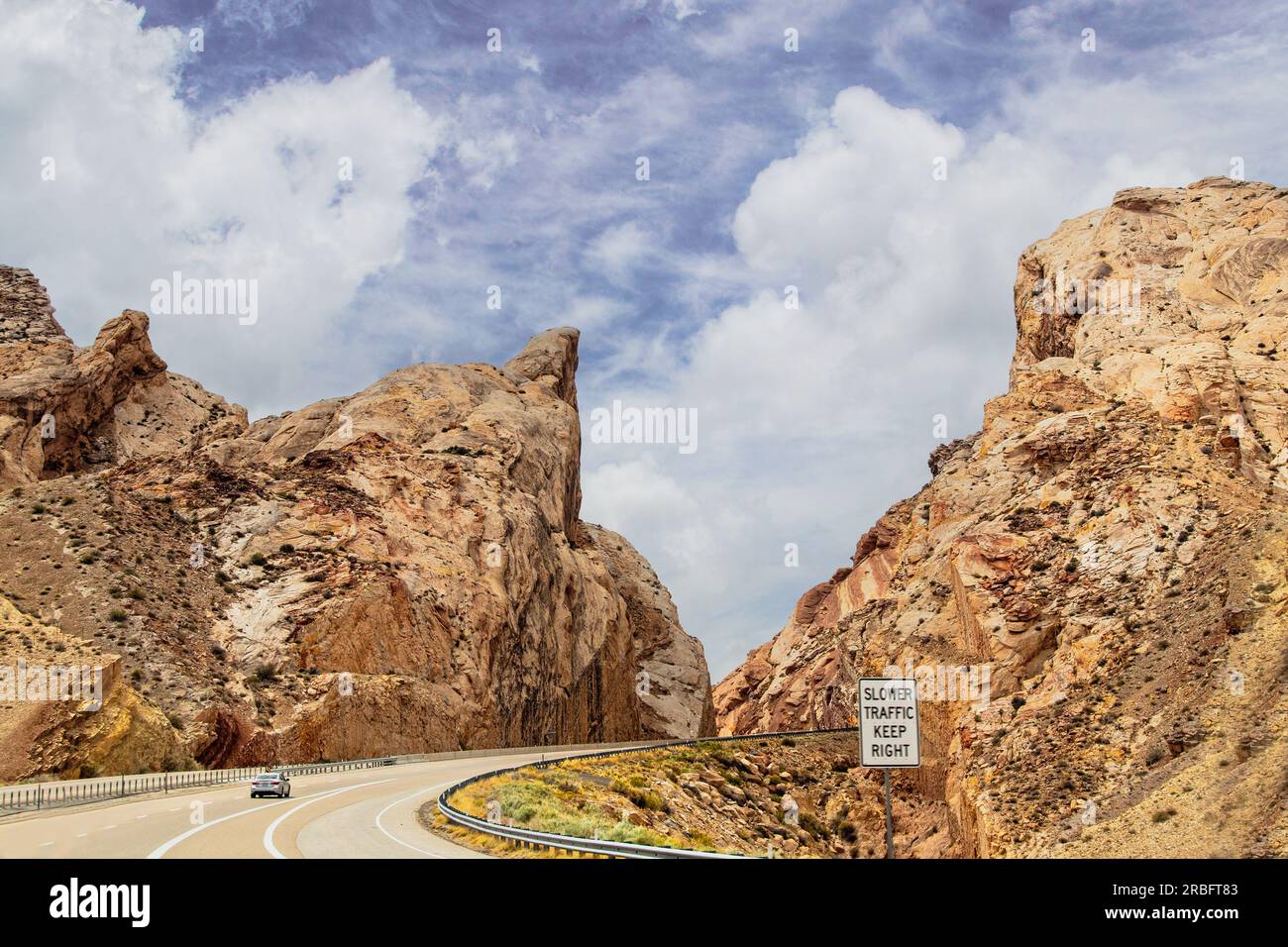 Highway cut through weirdly shaped barren mountains with car making ...