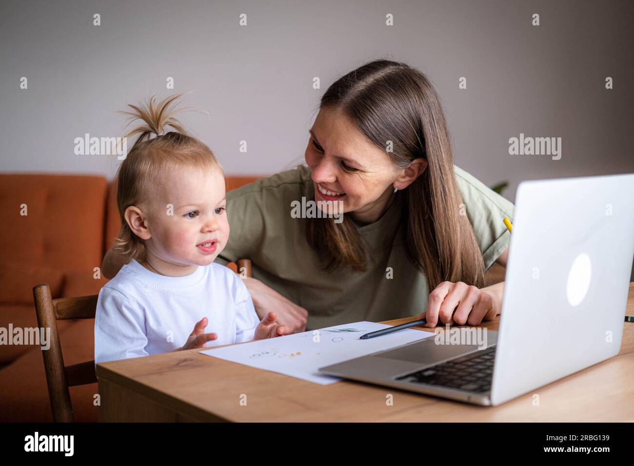 happy family mother and little baby daughter do homework using laptop ...