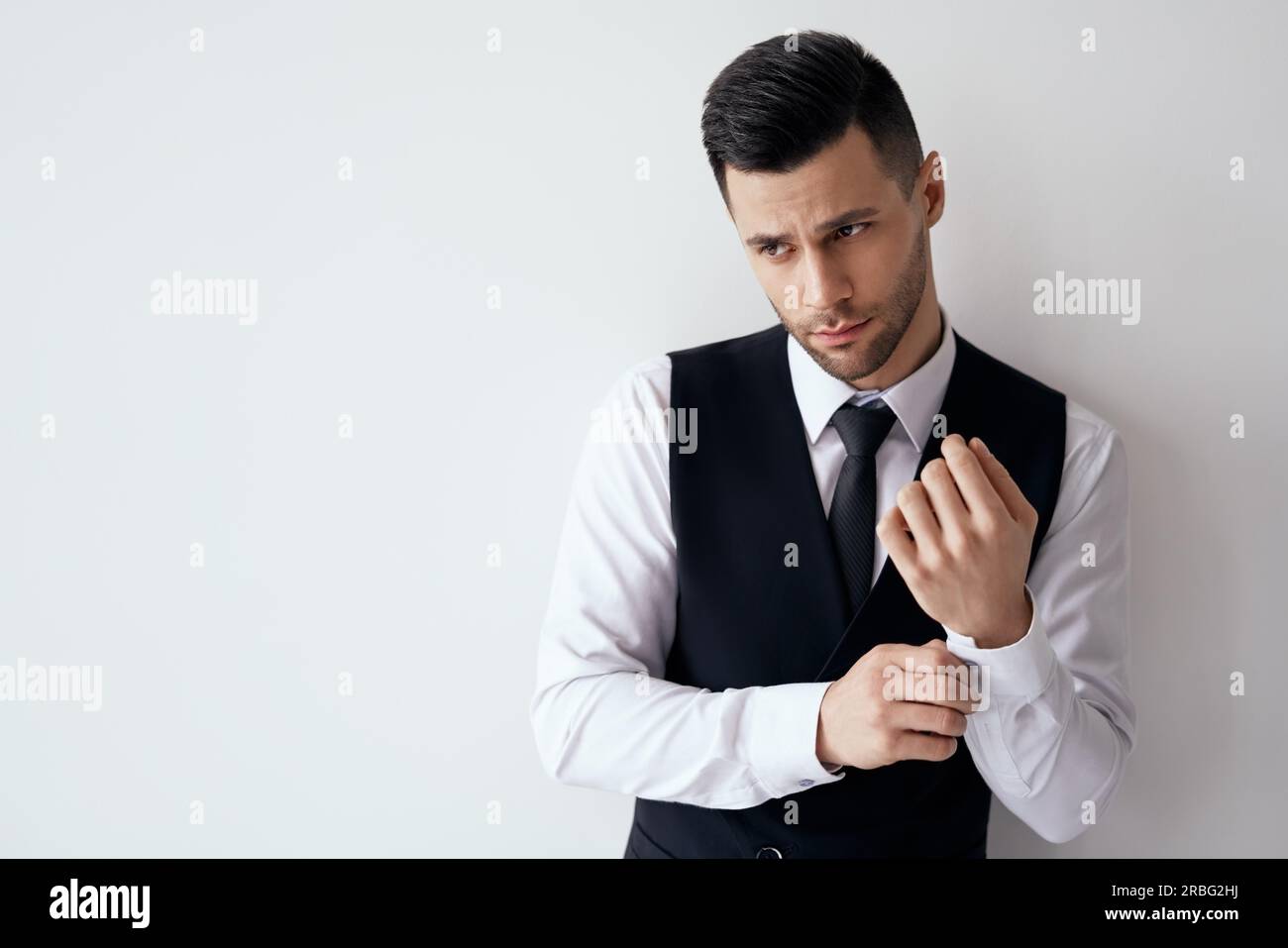 Handsome young man adjusting his sleeves and fixing his cufflinks ...