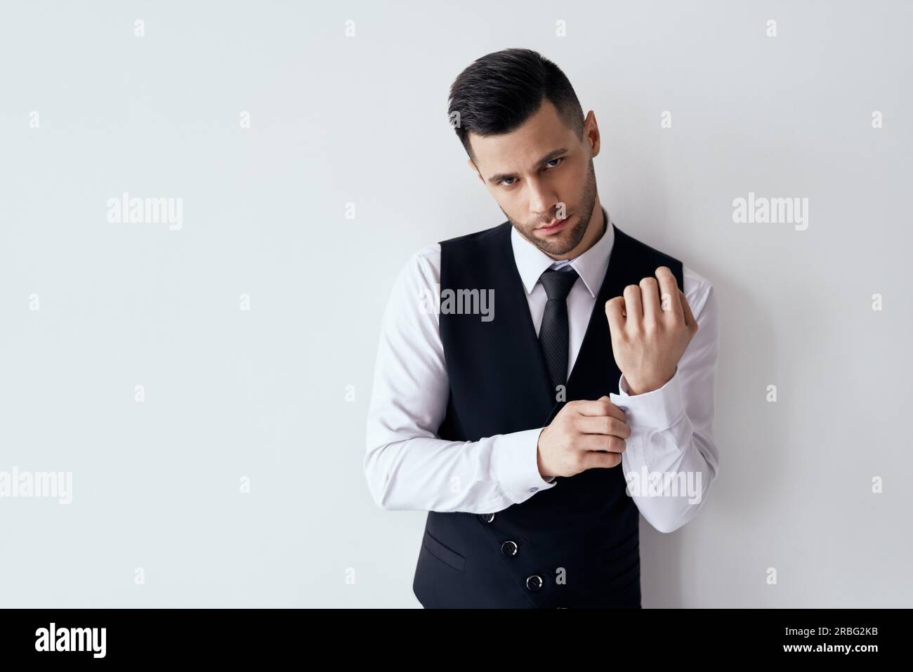 Handsome young man adjusting his sleeves and fixing his cufflinks ...