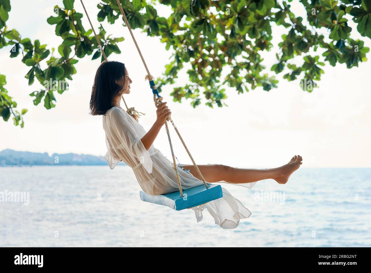 Carefree happy woman on swing on beautiful paradises beach. Relax and ...