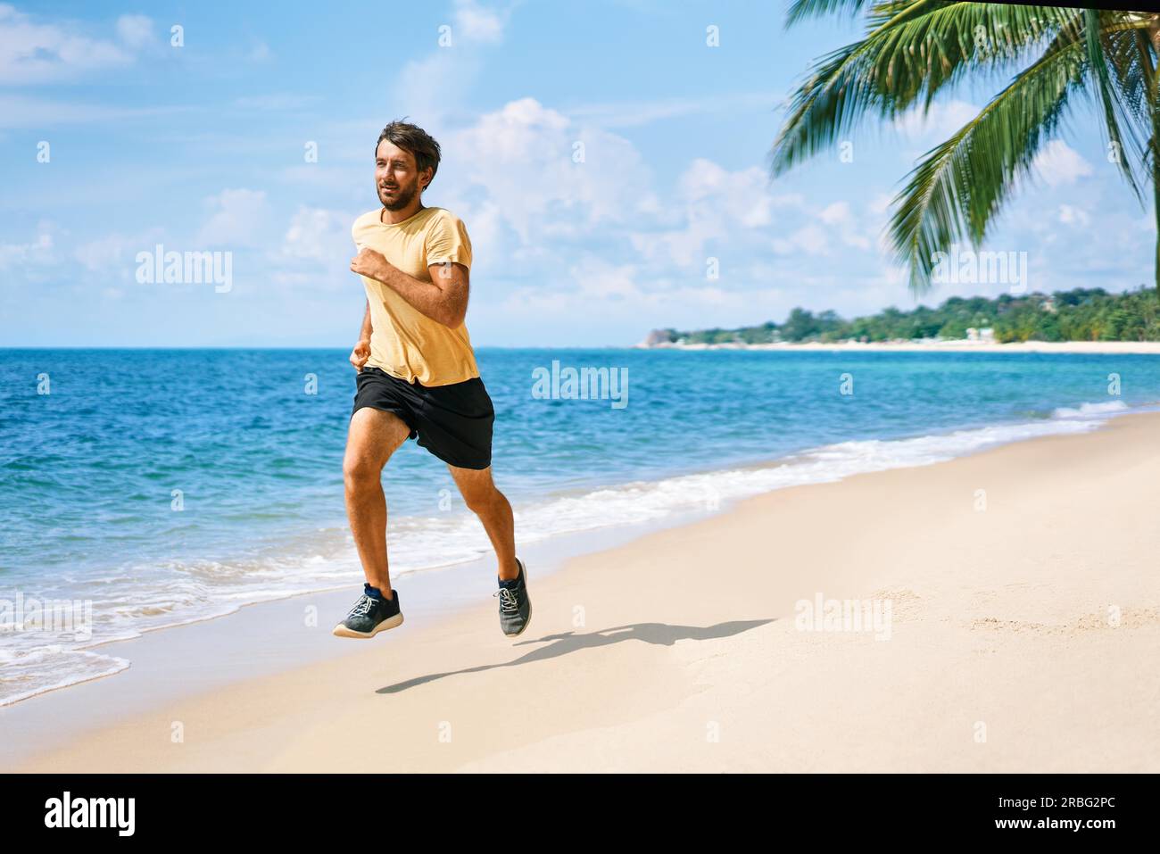 Young man running on the sea shore of tropical beach. Healthy lifestyle ...