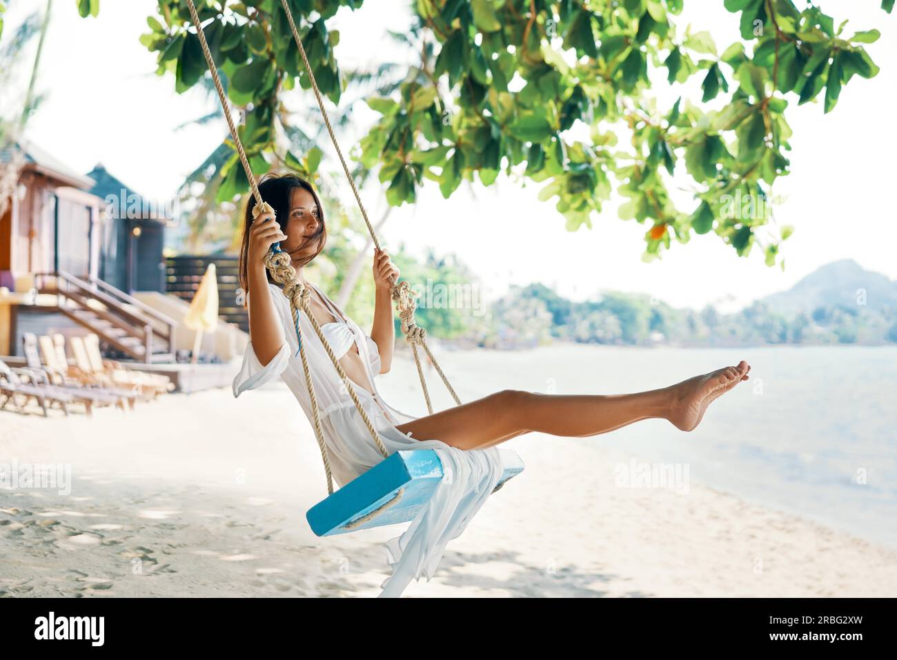 Carefree happy woman on swing on beautiful paradises beach. Relax and ...