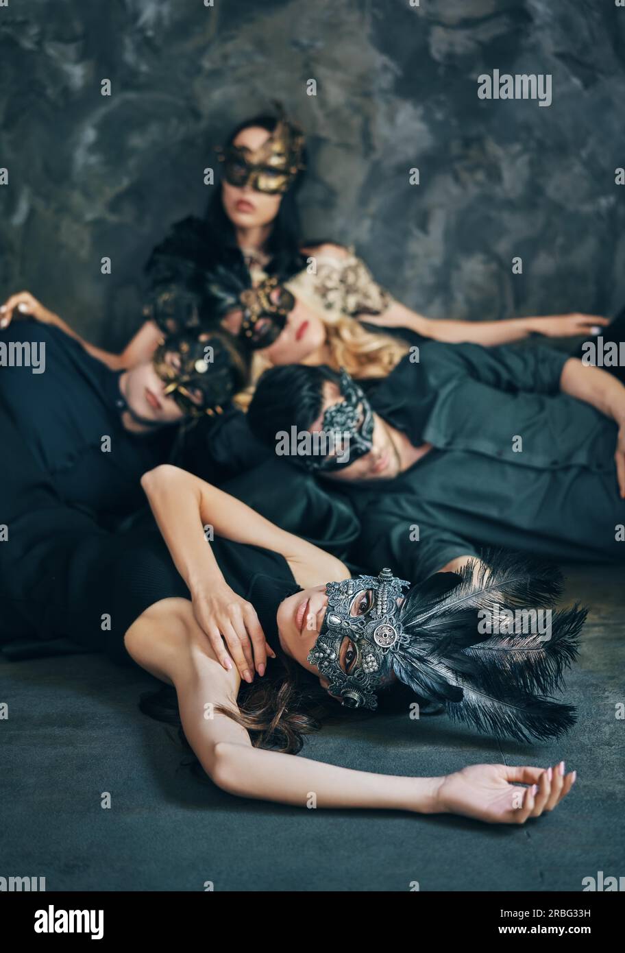 Group of friends in masquerade carnival mask sitting on floor relax ...