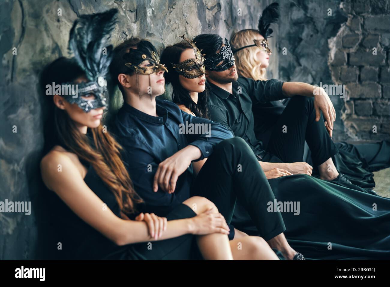 Group of friends in masquerade carnival mask sitting on floor relax ...