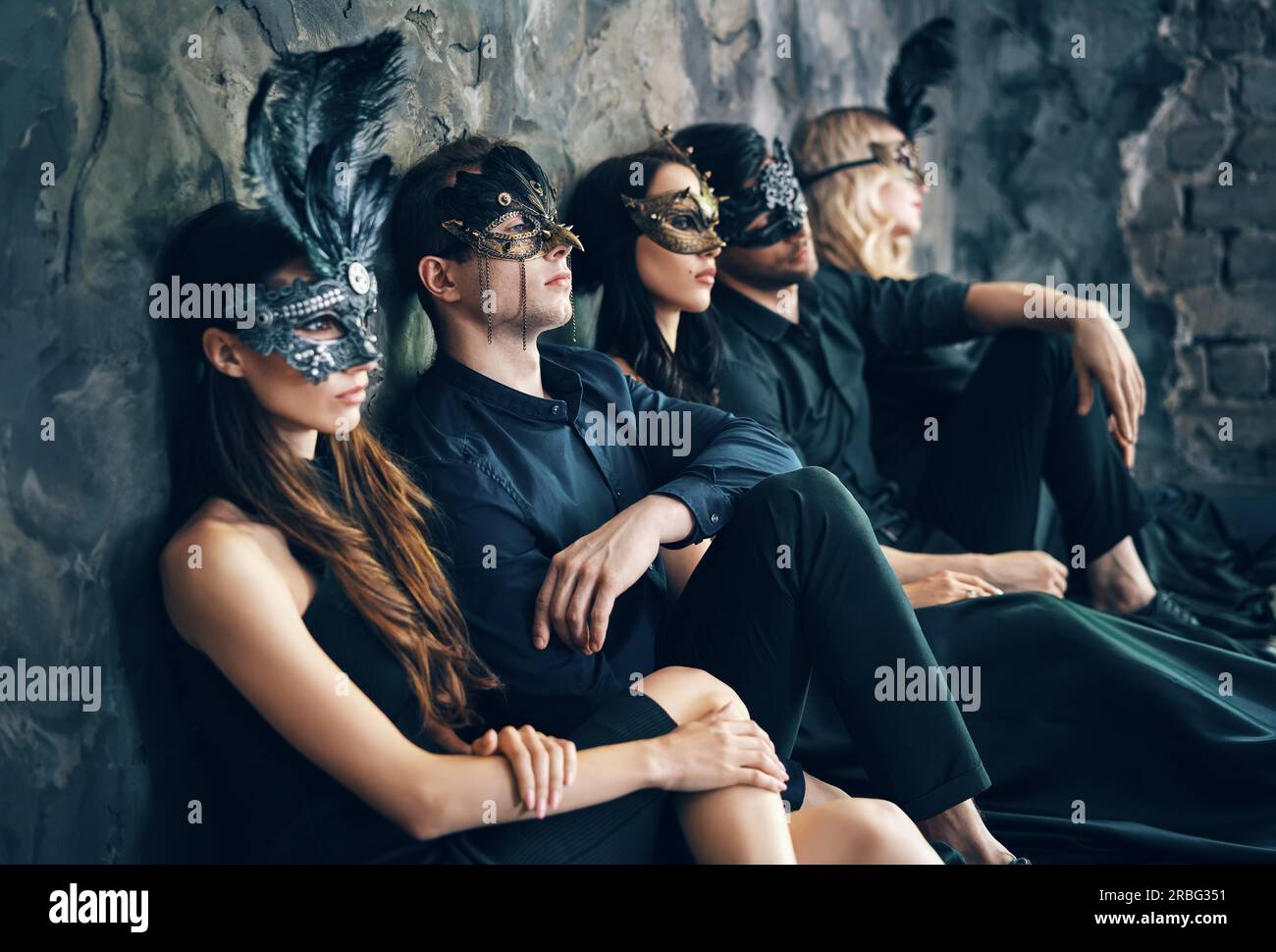 Group of friends in masquerade carnival mask sitting on floor relax ...