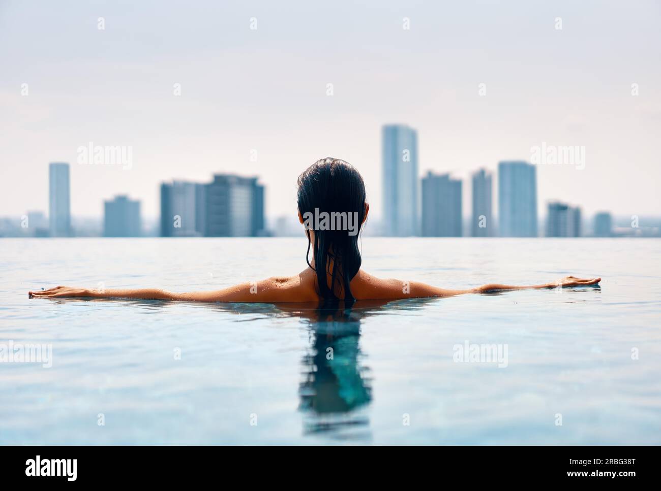 Enjoy vacation. Back view of young woman swimming in swimming pool on ...