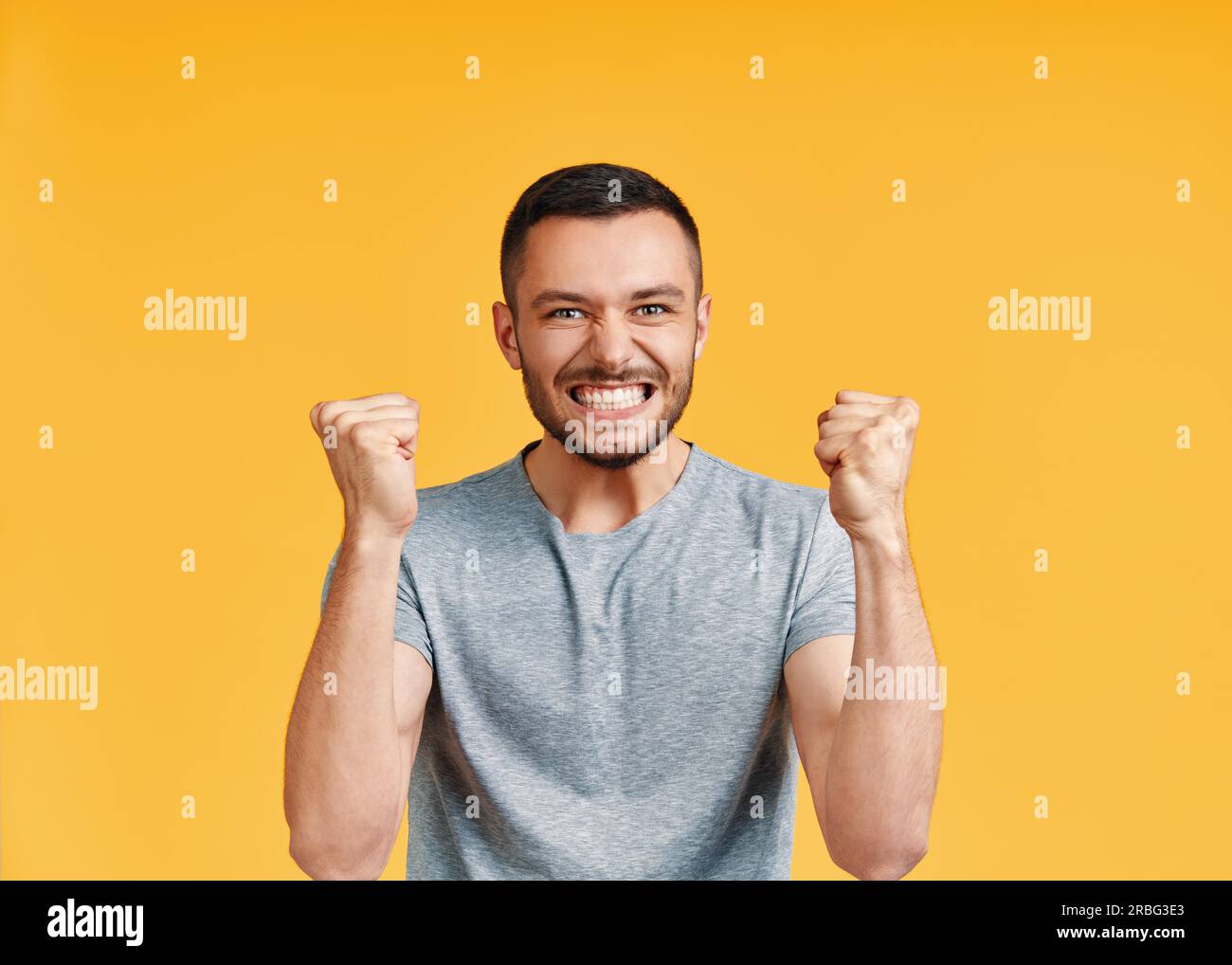Happy man celebrating his success with winner gesture on yellow ...