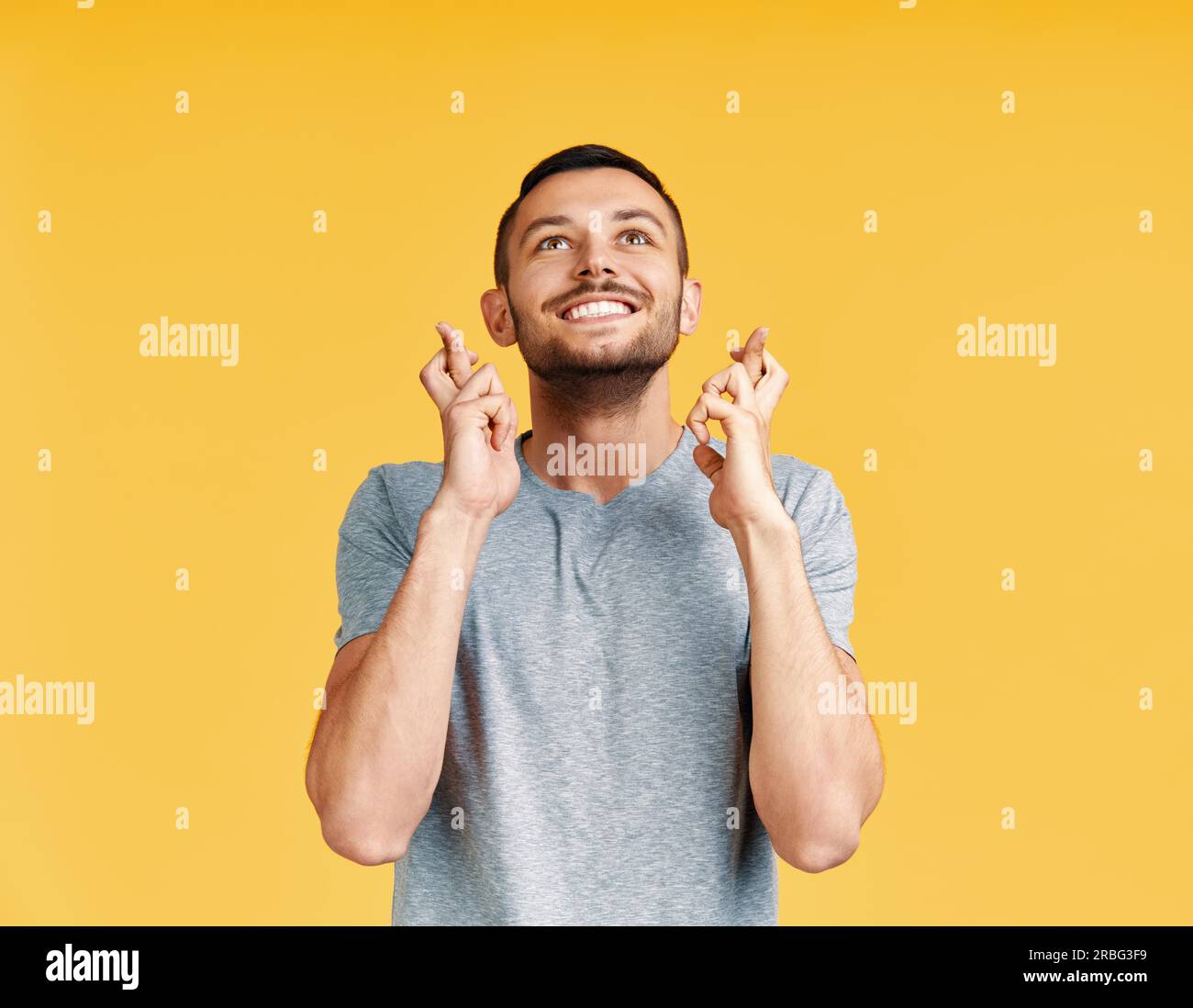 Young man making a wish and ask for good luck with crossed fingers ...