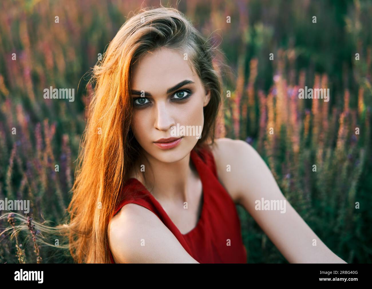 Portrait of beautiful young woman posing in sage field in summer sun ...