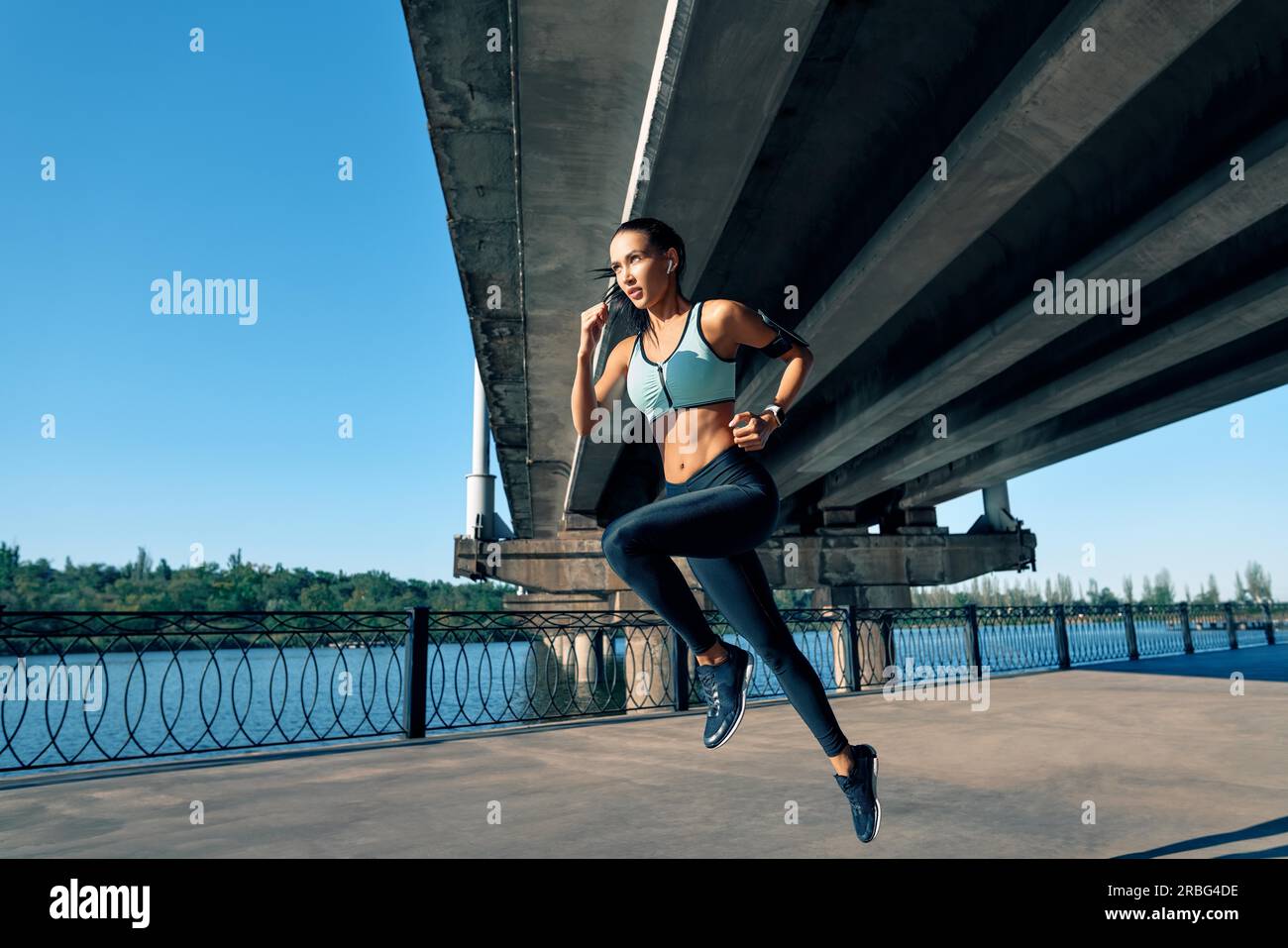 Sporty woman running outdoors by river. Beautiful woman in sportswear ...