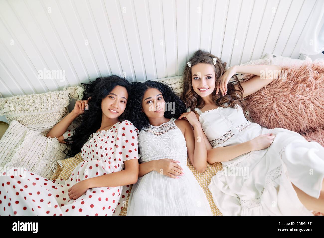Beautiful multi ethnic girls have fun together, relax and lying on bed ...