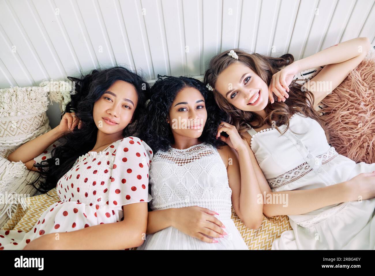 Beautiful multi ethnic girls have fun together, relax and lying on bed ...
