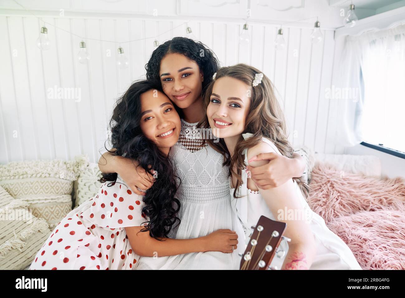 Three beautiful smiling girl friends hugging each other in a close ...