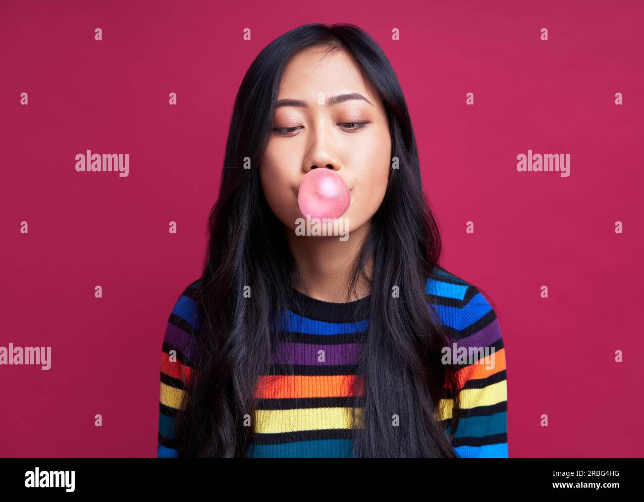 Pretty young woman blowing bubble with chewing gum isolated over pink ...