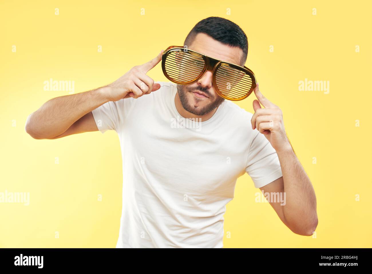 Young man in funny party glasses over yellow background. Fun concept ...