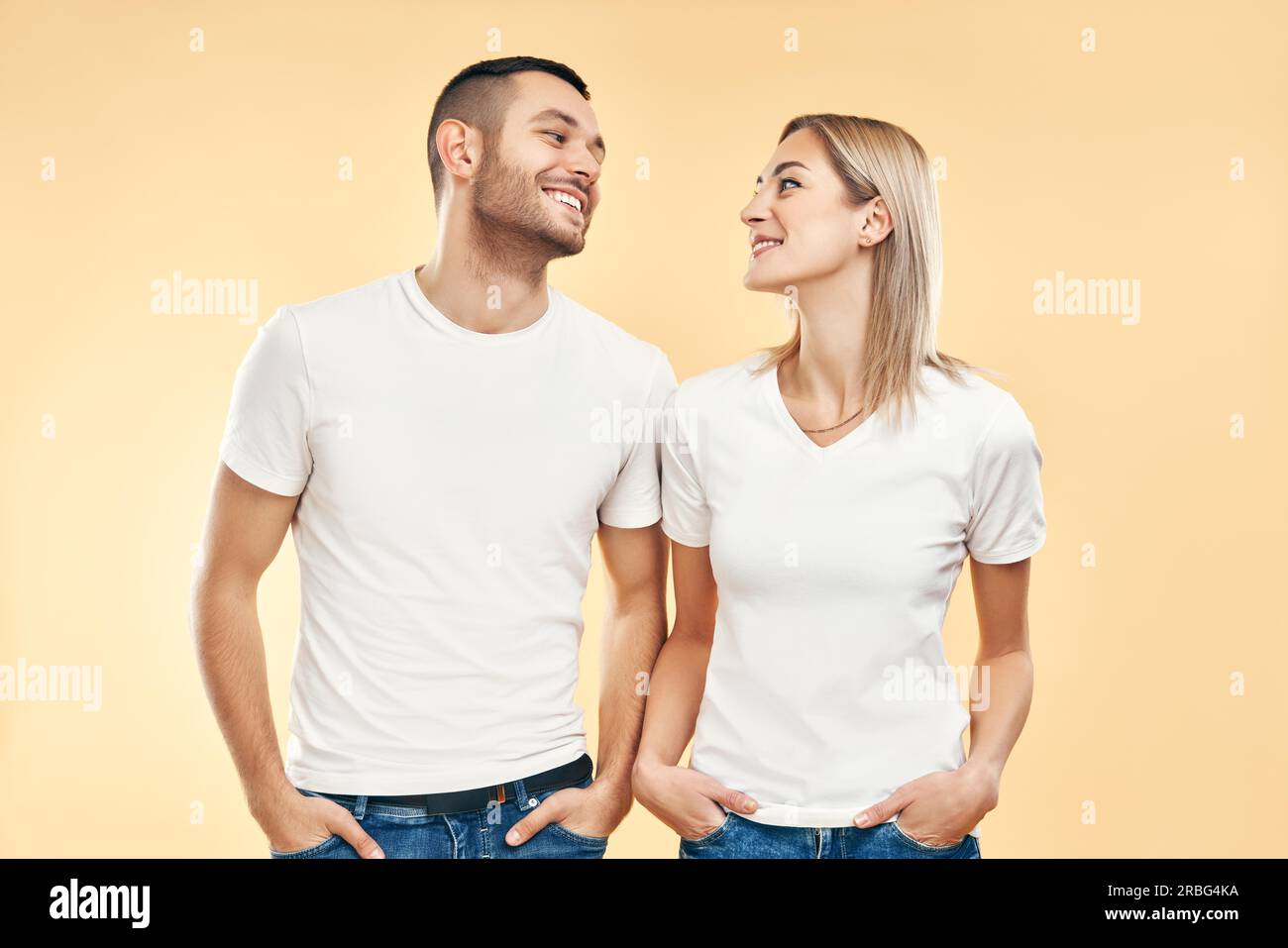 Young happy couple in love look to each other over beige background ...