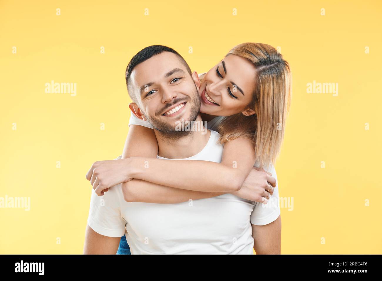 Happy smiling couple in love on yellow background. Man carrying his ...