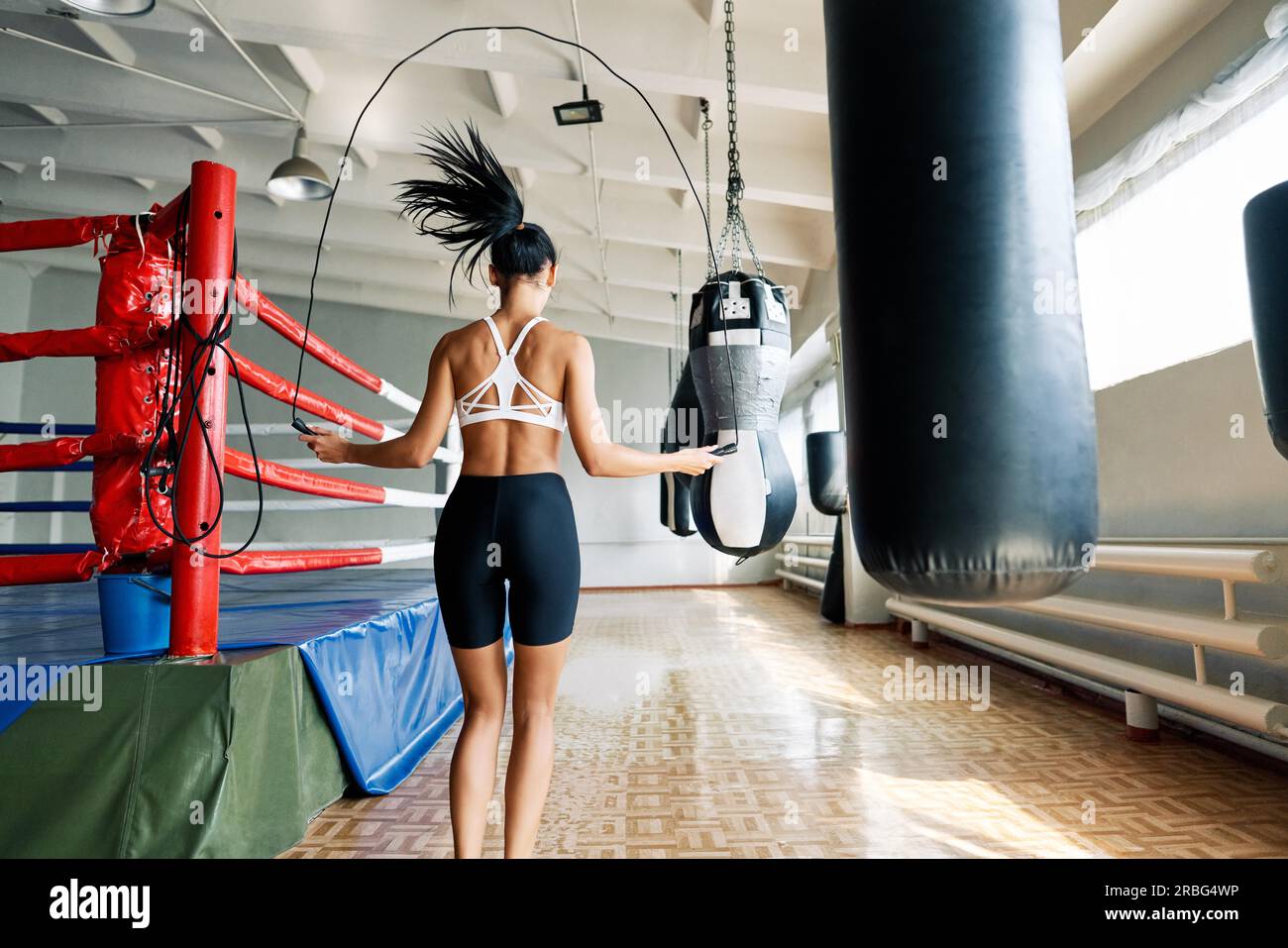 Back view of fitness woman skipping rope in gym. Cardio and fitness ...
