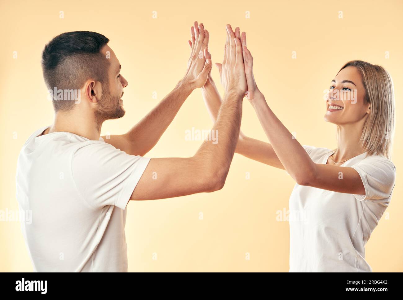 Portrait of young smiling couple giving high five to each other over ...