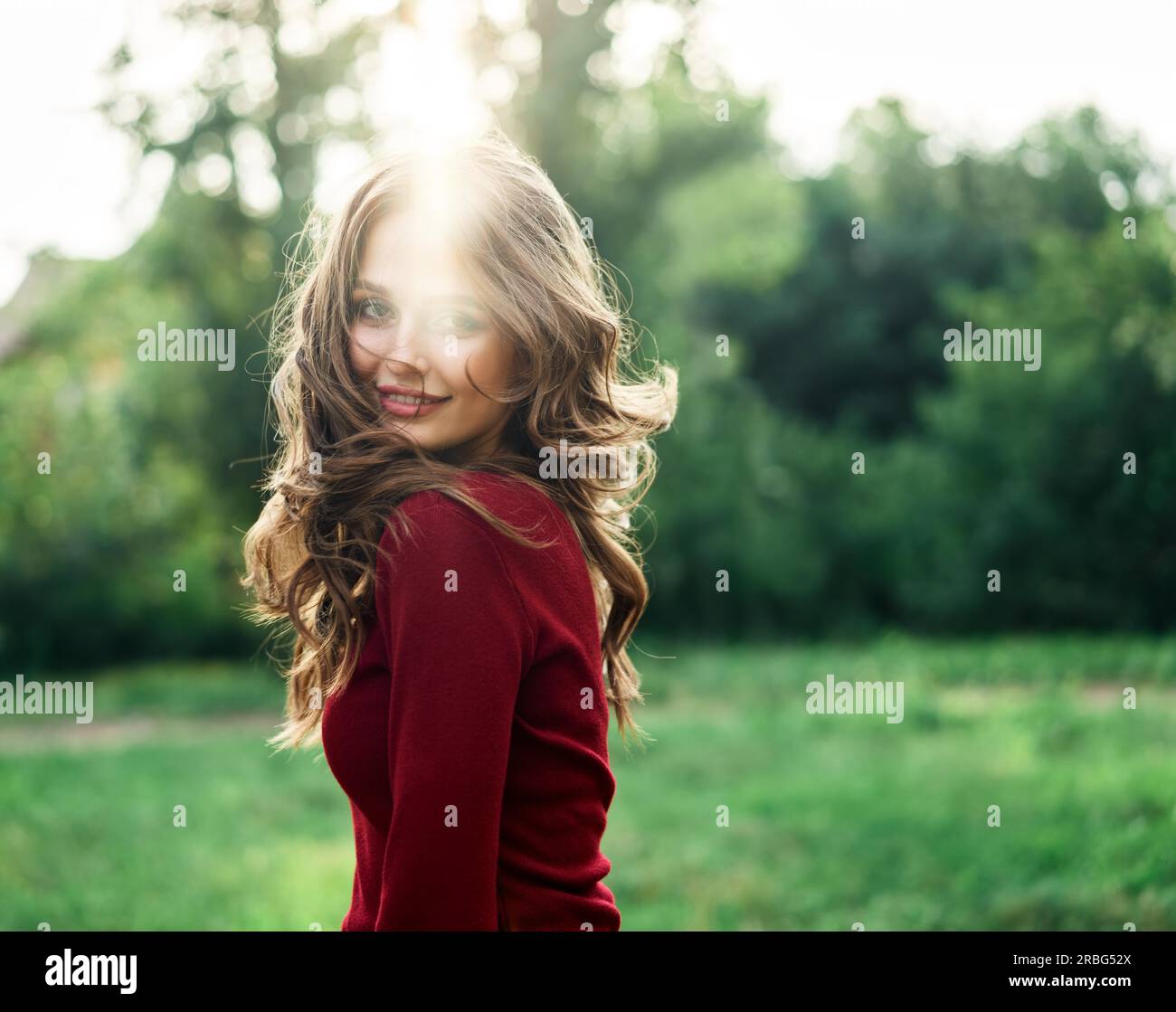 Young beautiful woman with backlit posing outdoors on green summer ...
